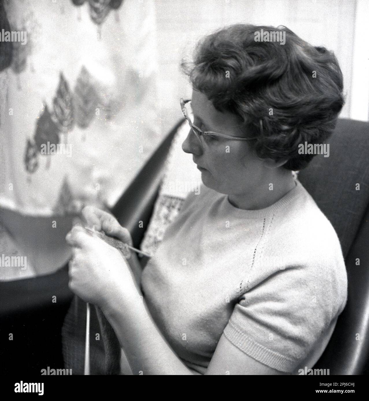 1960, historical, inside a room, a woman sitting knitting, England, UK ...