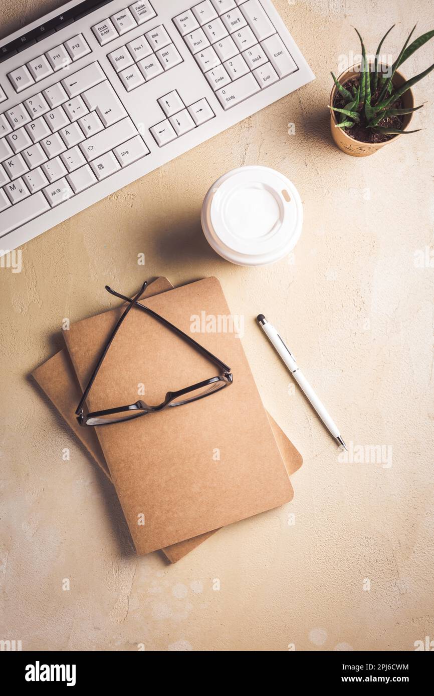 Modern office desk table with laptop computer, notepad, tablet, plant, glasses and pen with cup ...