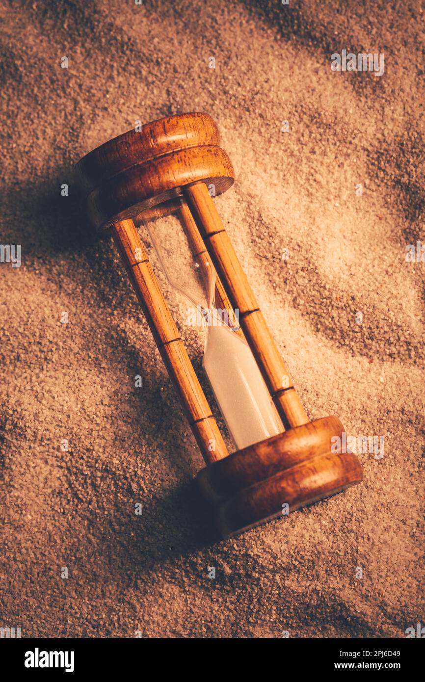 Old sandtimer in sand in vitange look. Concept of time, age and history ...