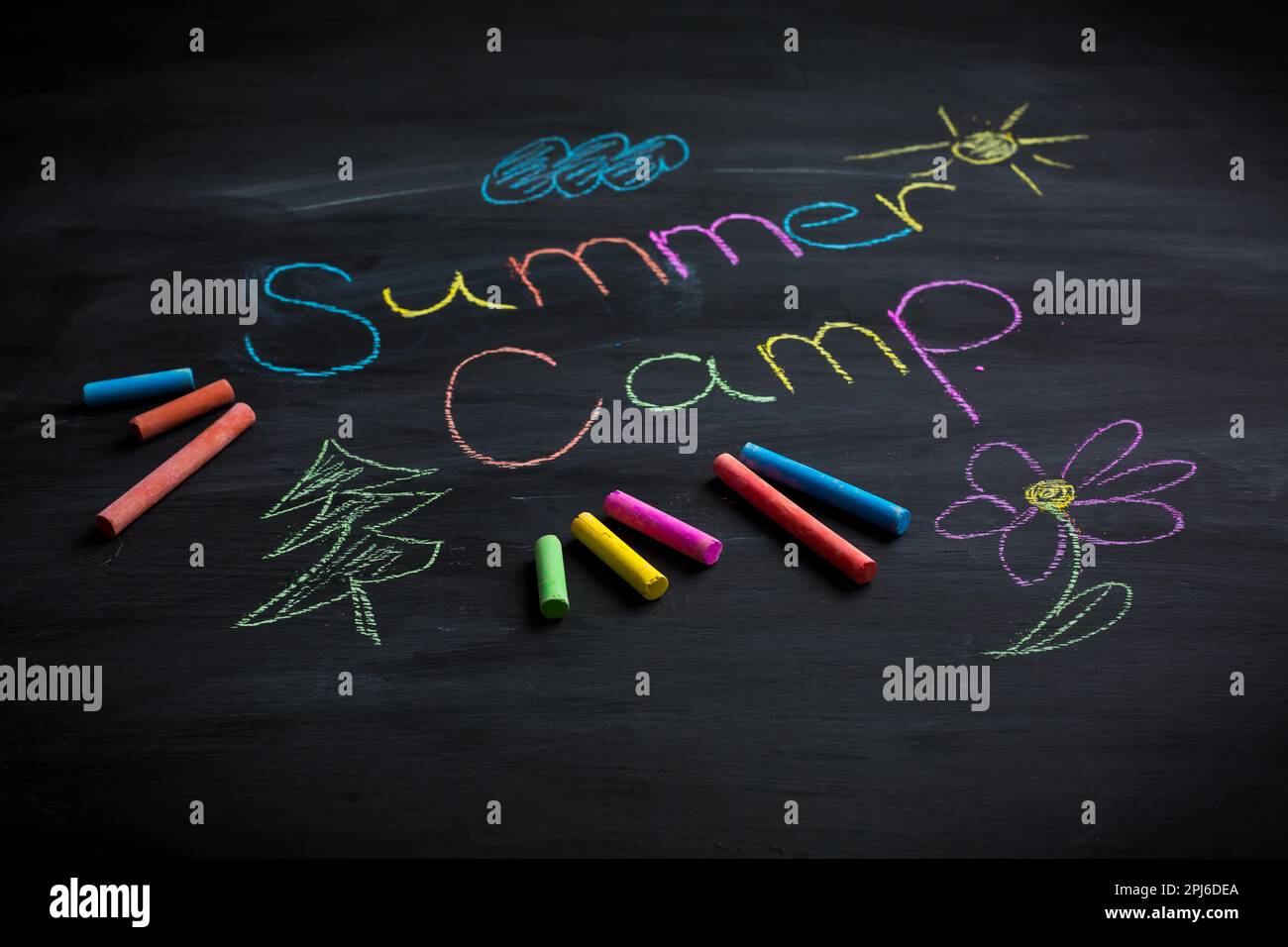 Text Summer camp written on black chalkboard, with chalk sticks of ...