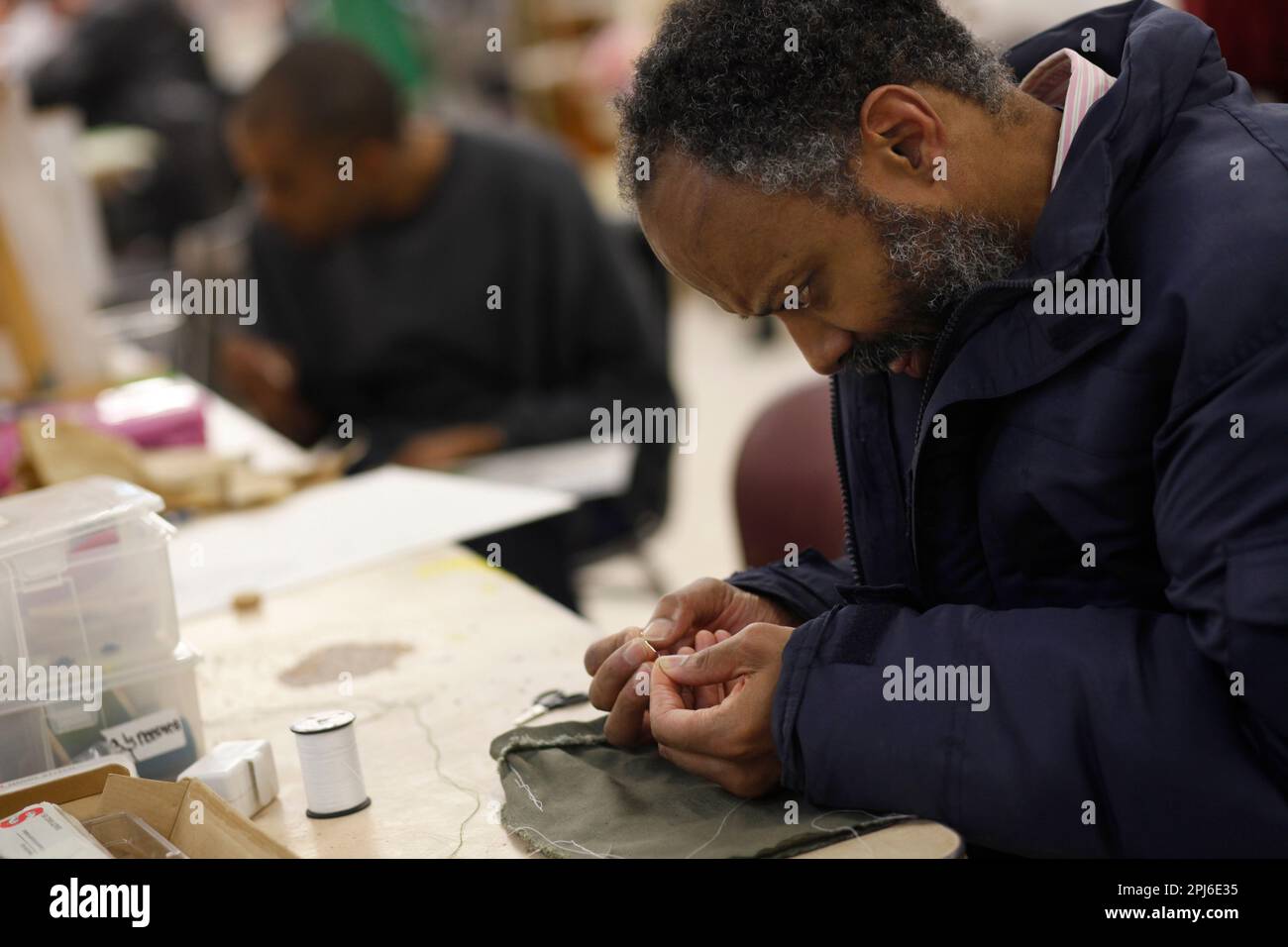 Rodney Eugene Jones threads a needle as he works on a weave bag at ...