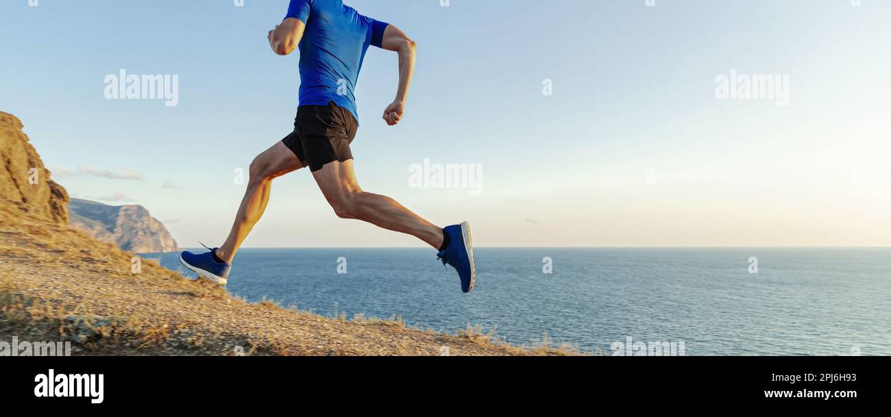 male runner running mountain sea trail on withered grass, cross-country ...