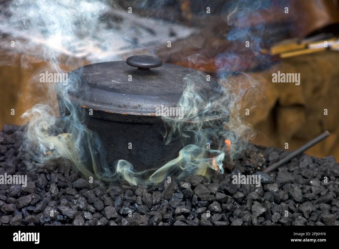 Cast iron pot on the charcoal for tempering the forged material Stock ...
