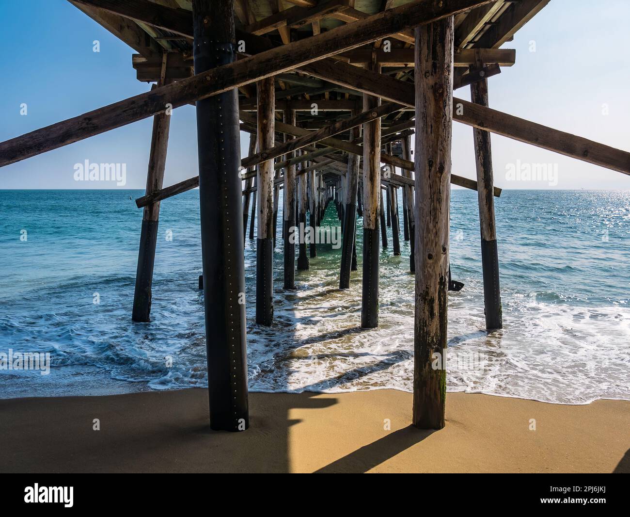 The wooden poles under the pier on the coast stretch over a deep blue ...