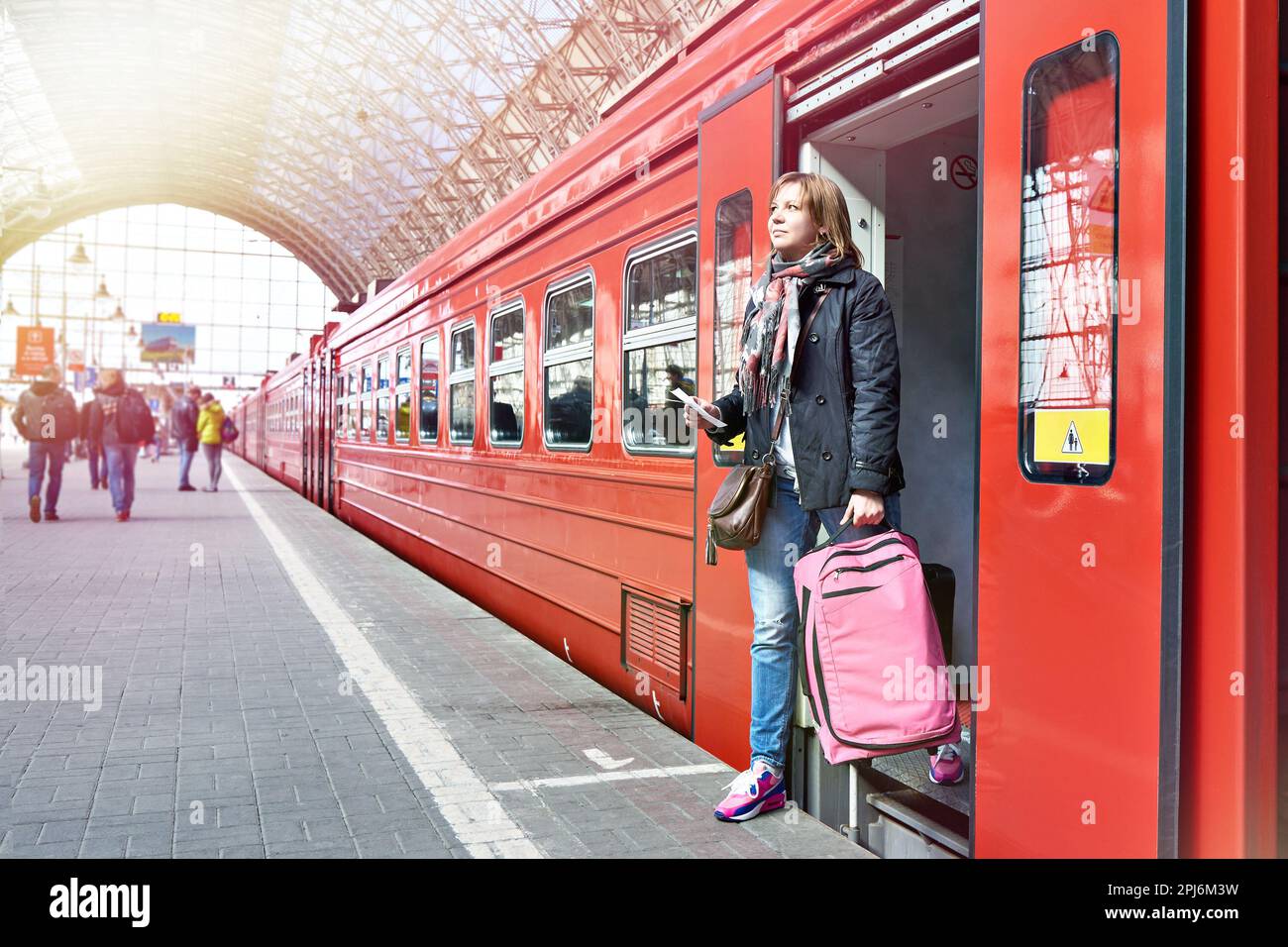 Woman tourist with a suitcase coming out of the train at the station ...