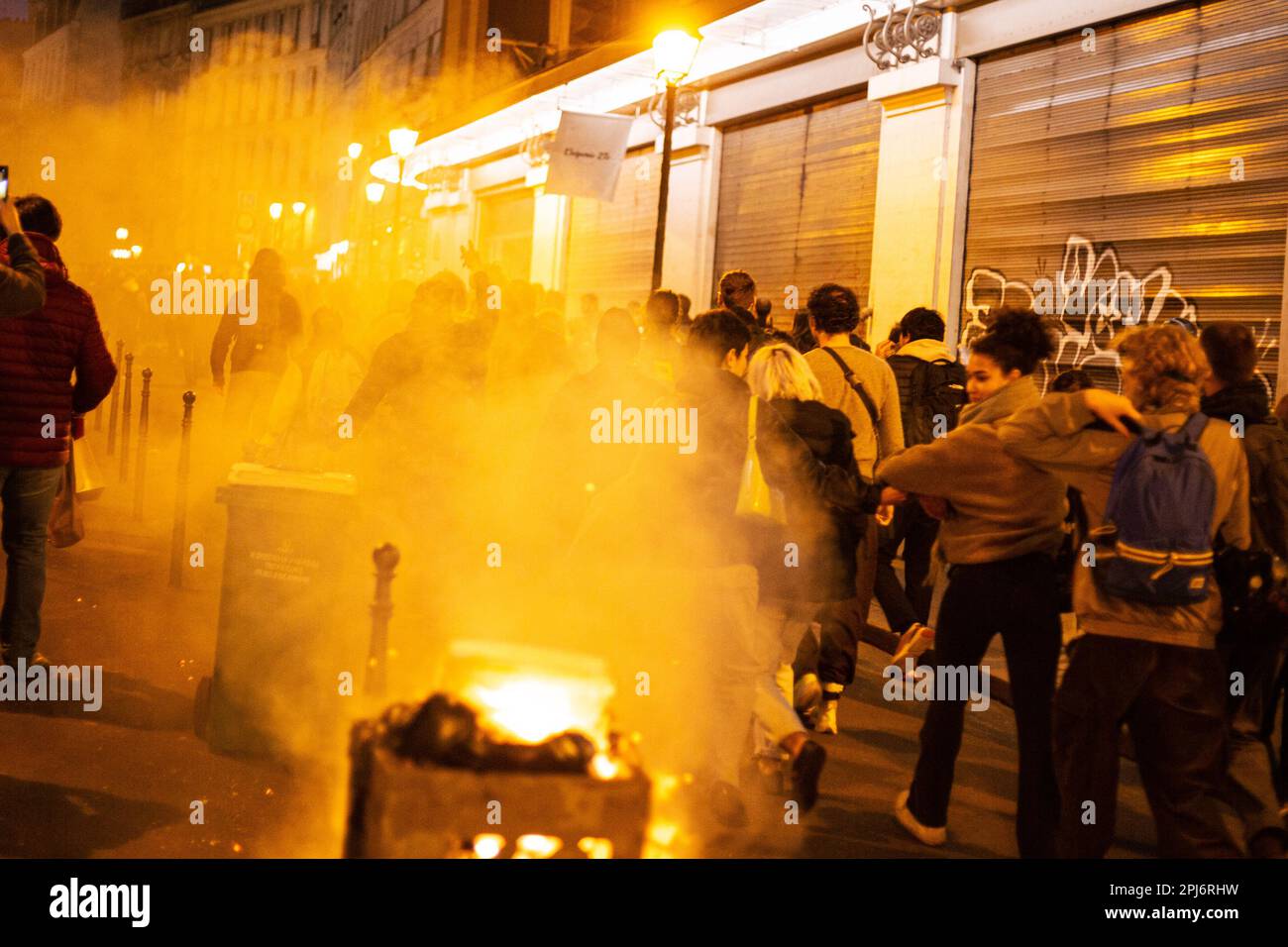 Paris, France. 30th Mar, 2023. Protesters walk past a garbage bin on ...