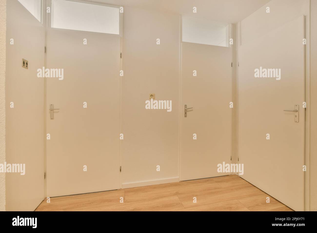 an empty room with wooden floors and white walls, two closed doors on ...