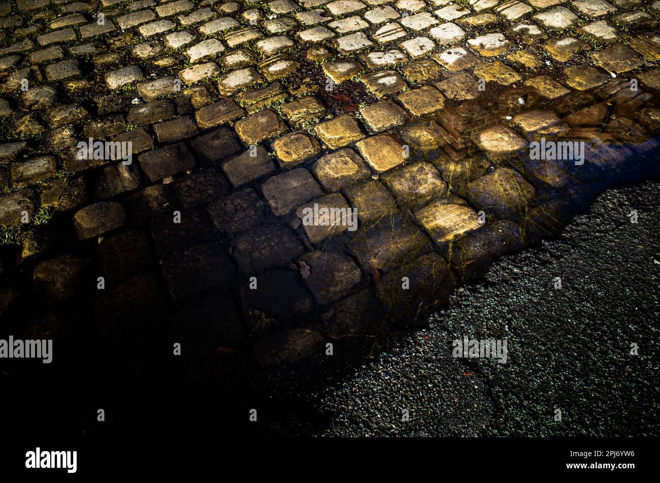 Old cobble stones and tarmac road surface under a puddle Stock Photo ...