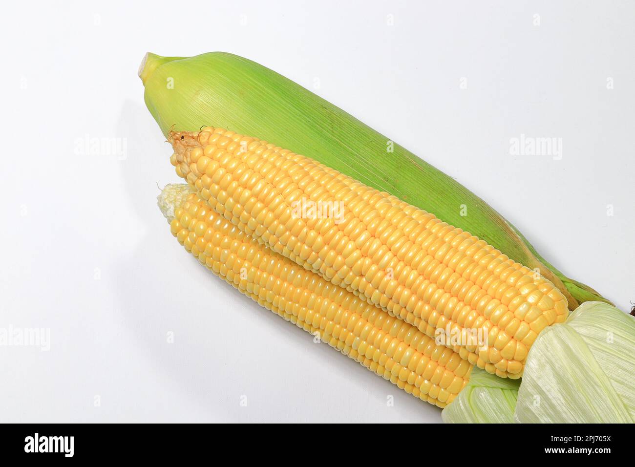 Fresh raw Corncobs or corn ears with green leaves isolated on white ...