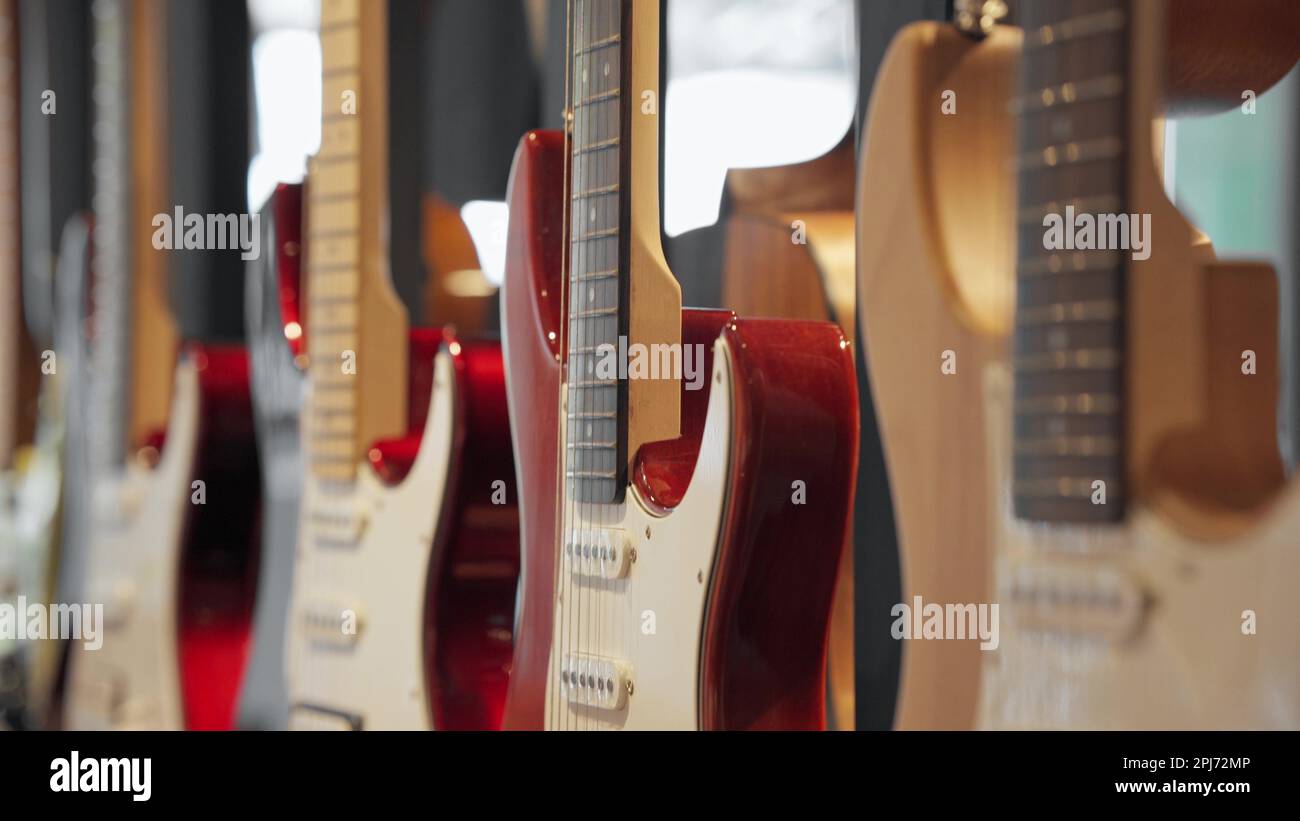 Electric guitars on display in an instrument store, hung on a wall ...