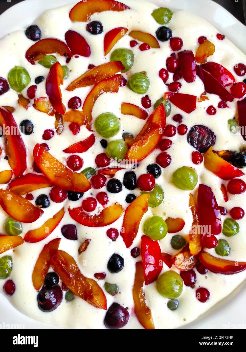 Plate of uncooked clafouti with berries and fruits. Close-up view from ...