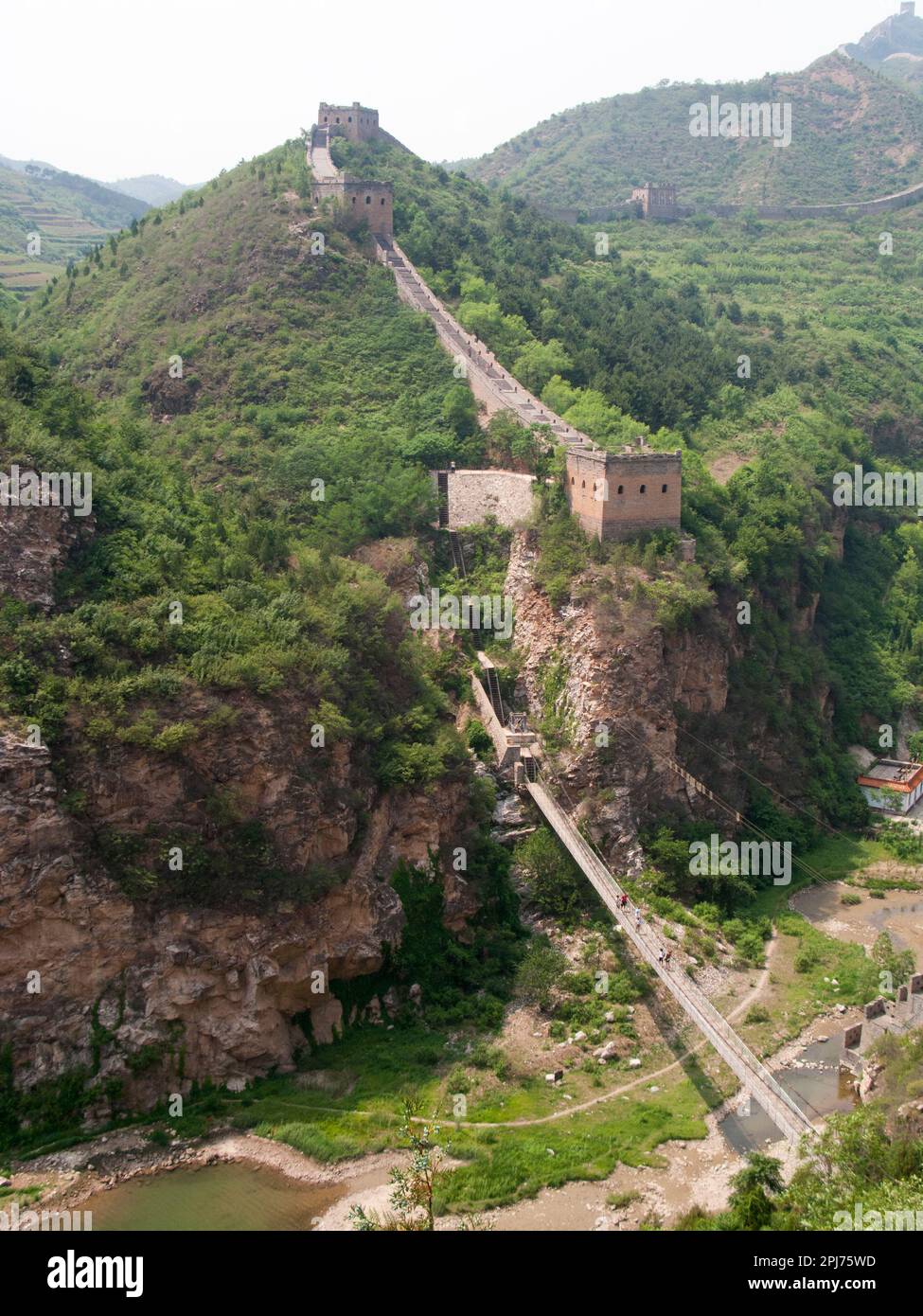 River spanned by suspension footbridge & overlooked watch tower guard ...