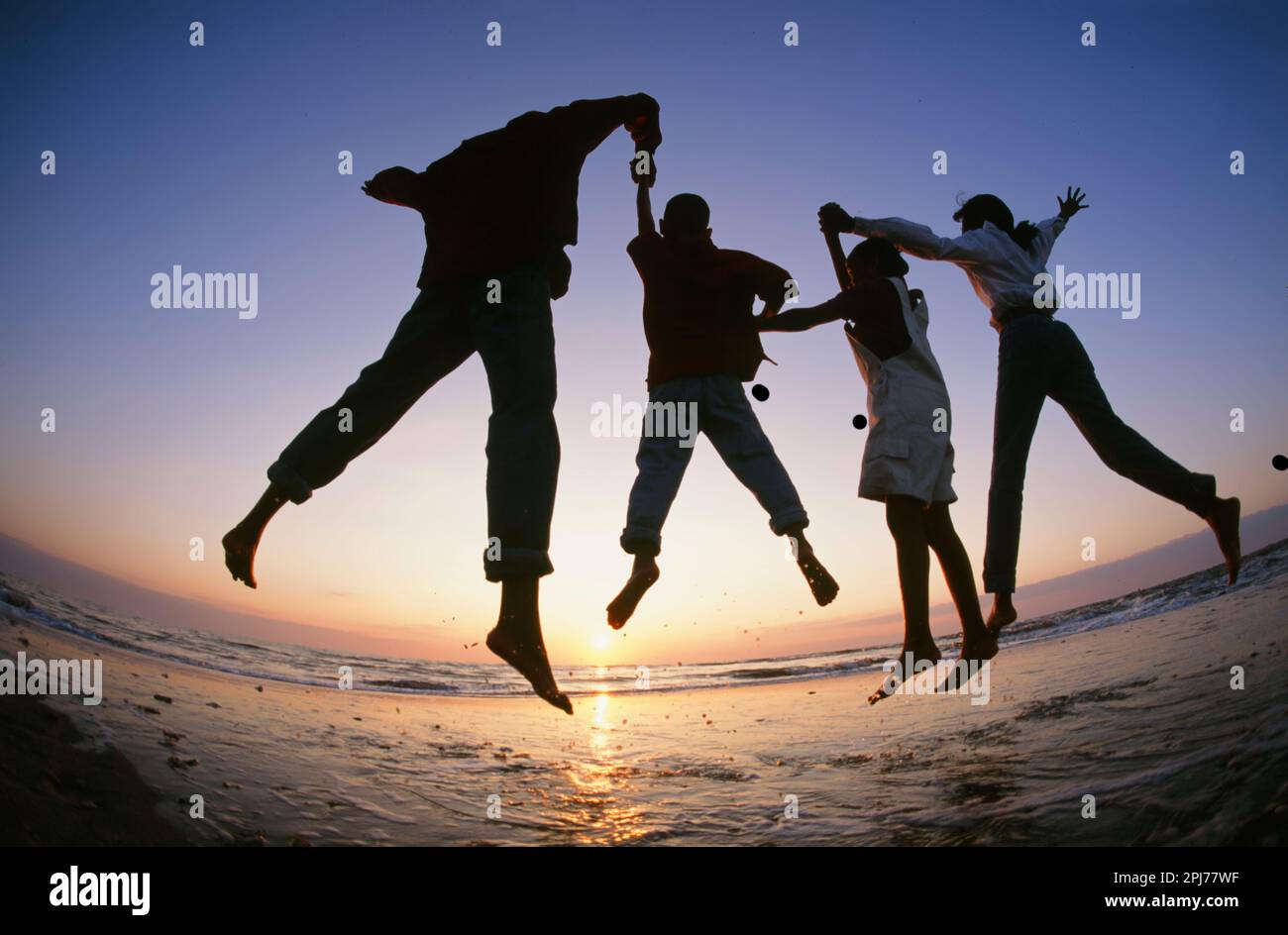 A family jumping for joy as they watch the sunrise over the Atlantic ...