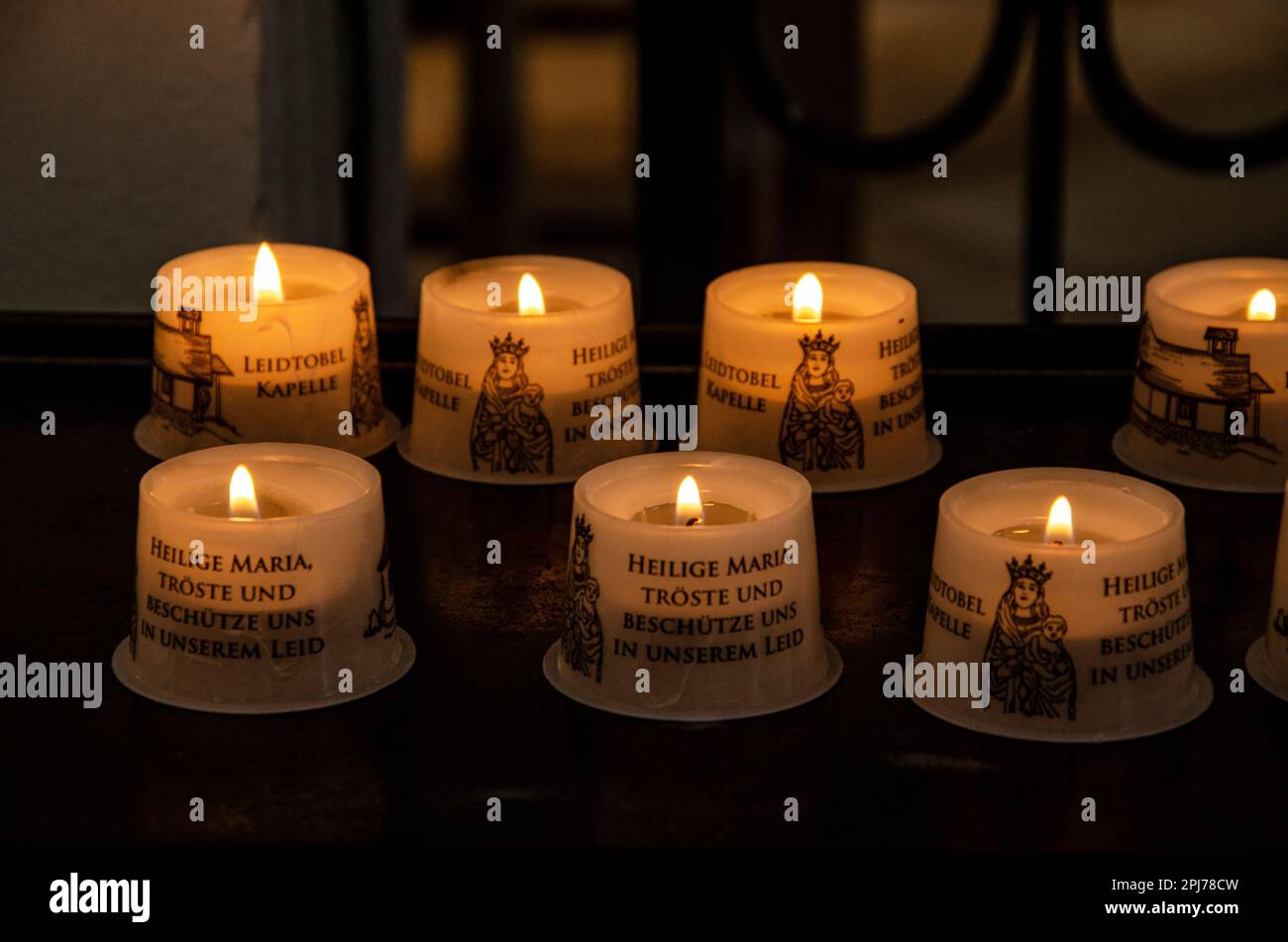 A set of lit church candles in a line with the illustration of the ...