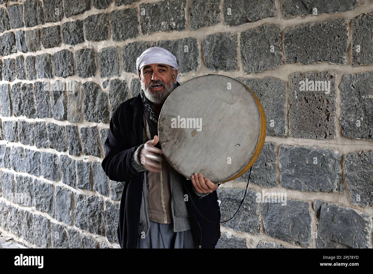 A street musician is seen playing tambourine and singing religious ...