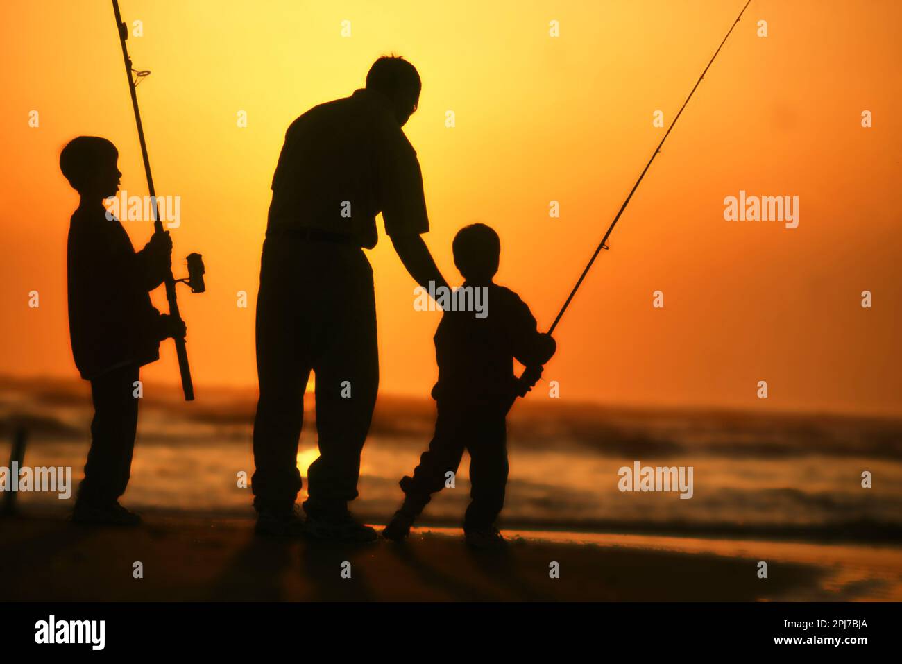 Silhouette of a father and his two sons fishing in the Lantic ocean at ...