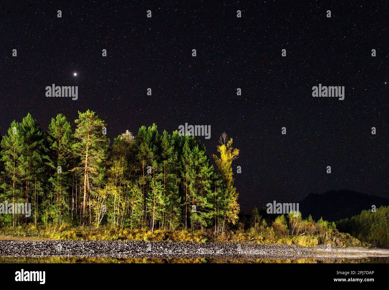 A bright star over a river with clear water with a stone shore, a ...