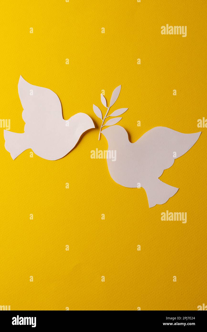 Close up of two white doves with leaf and copy space on yellow ...