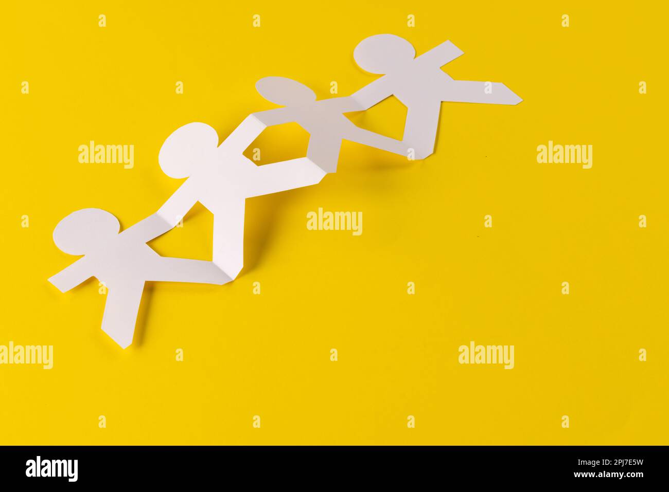 Close up of four paper cut out people figures holding hands with copy ...