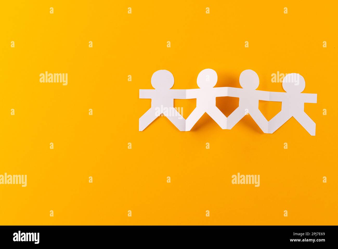 Close up of four paper cut out people figures holding hands with copy ...