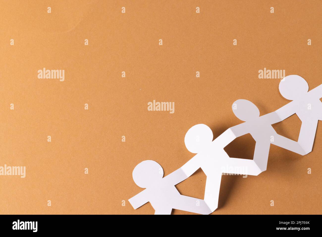 Close up of four paper cut out people figures holding hands with copy ...