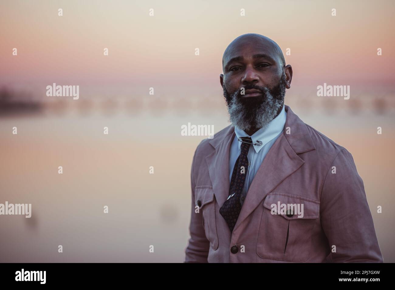 A black bald man with a stylish beard poses for a low-key portrait ...