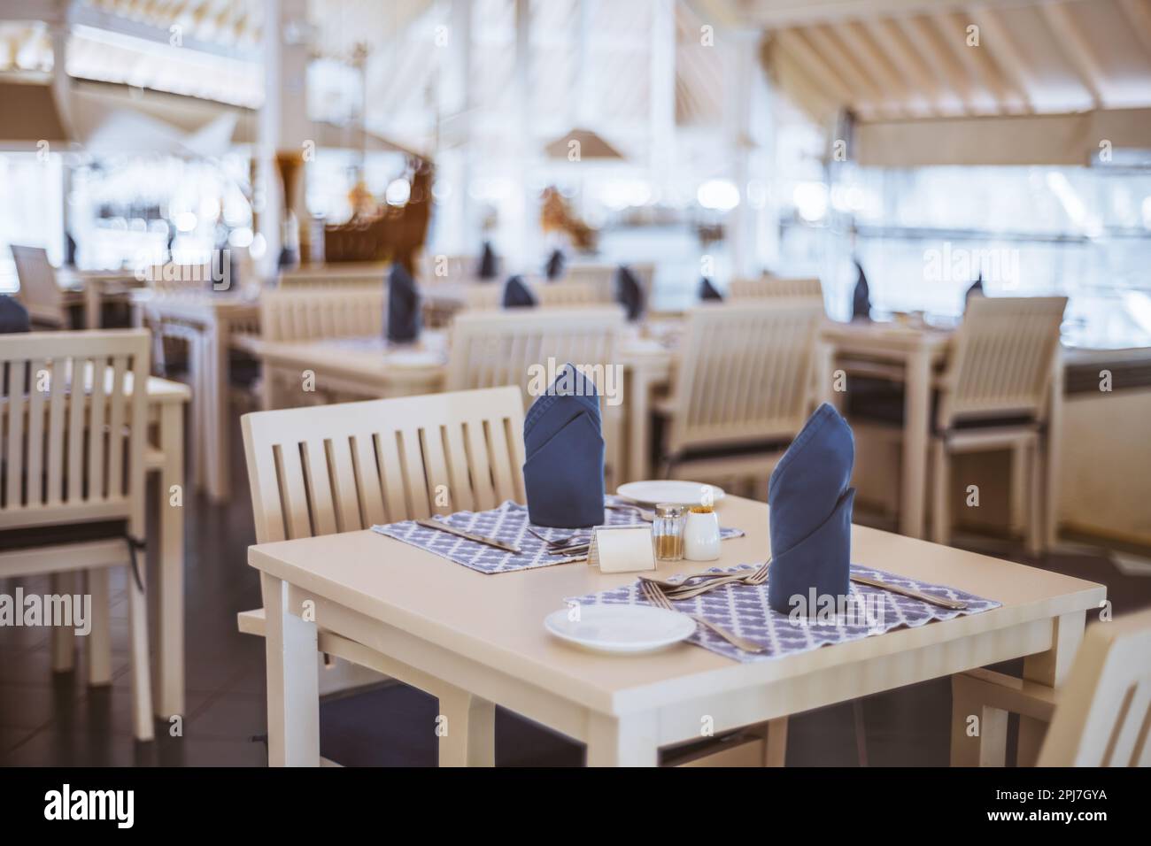 A single table with blue decoratively folded napkins, silverware, and a ...