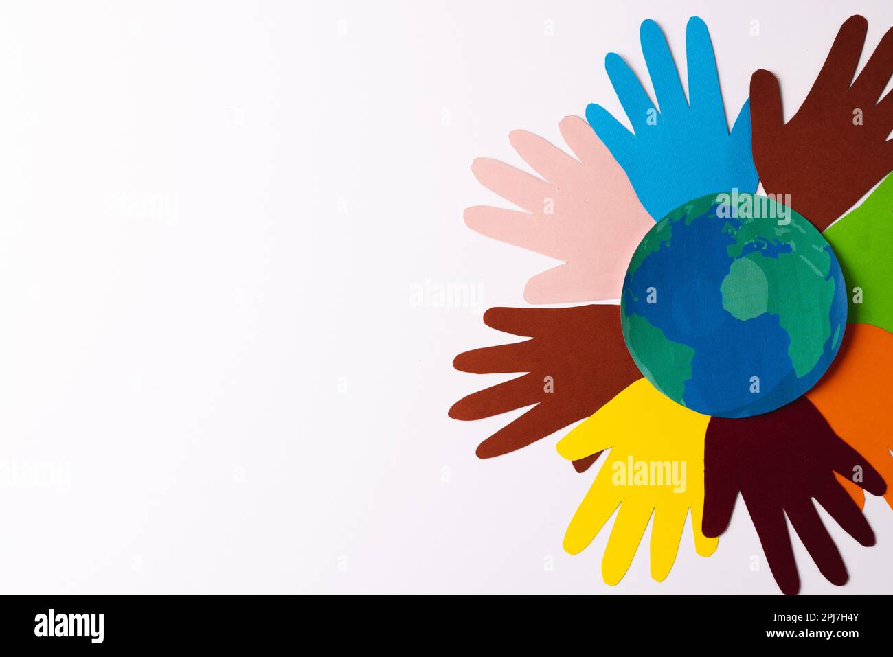 Paper cut out of multi coloured hands and globe with copy space on ...