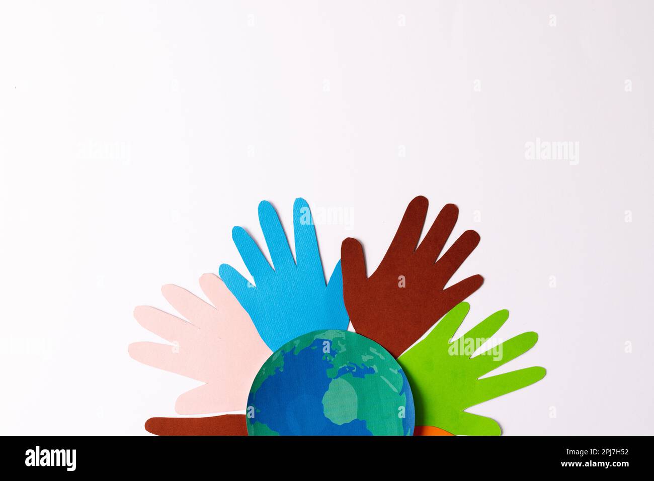 Paper cut out of multi coloured hands and globe with copy space on ...