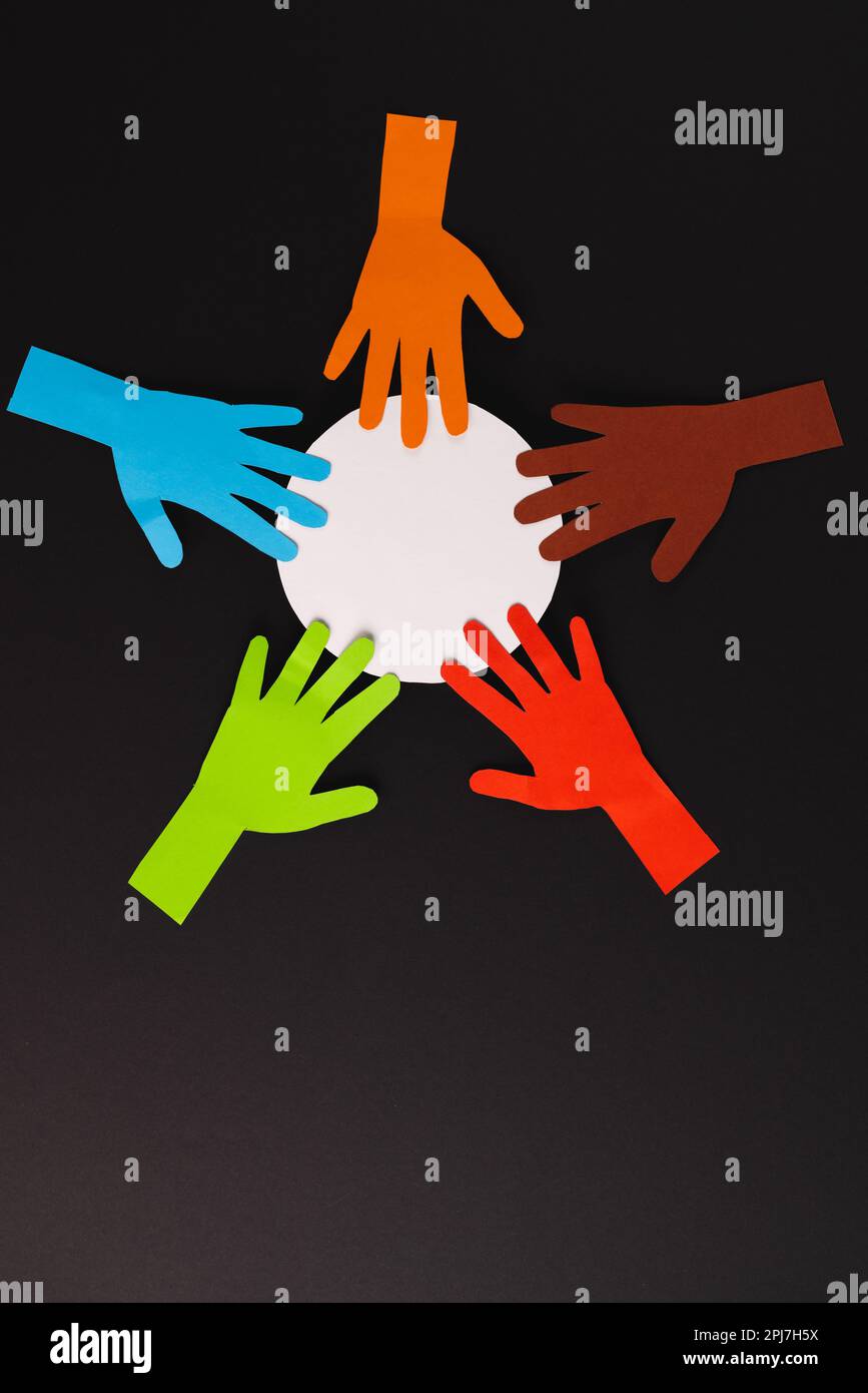 Paper cut out of multi coloured hands and white circle with copy space ...