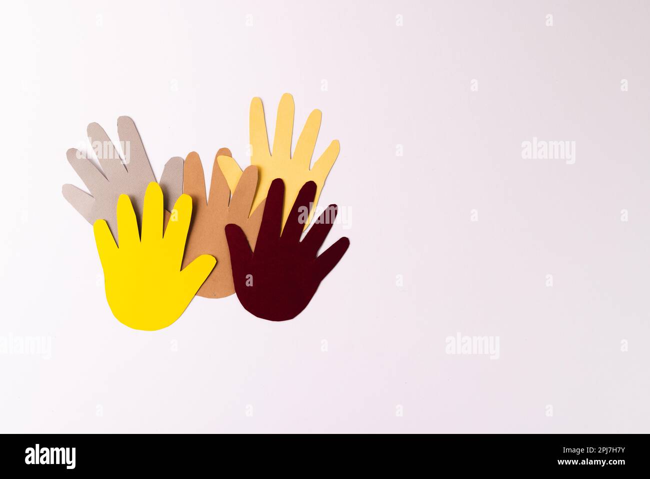 Paper cut out of multi coloured hands with copy space on white ...