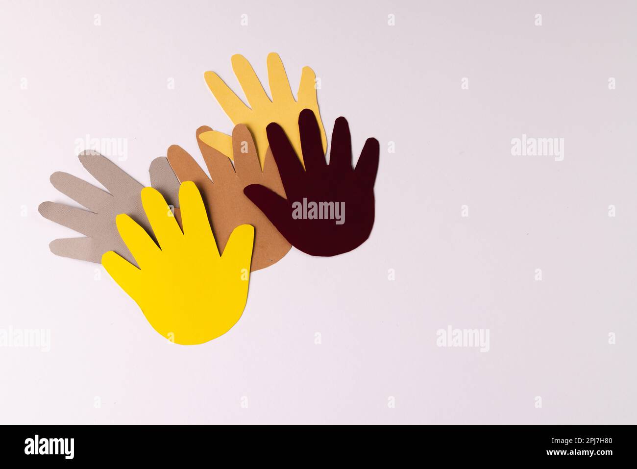 Paper cut out of multi coloured hands with copy space on white ...