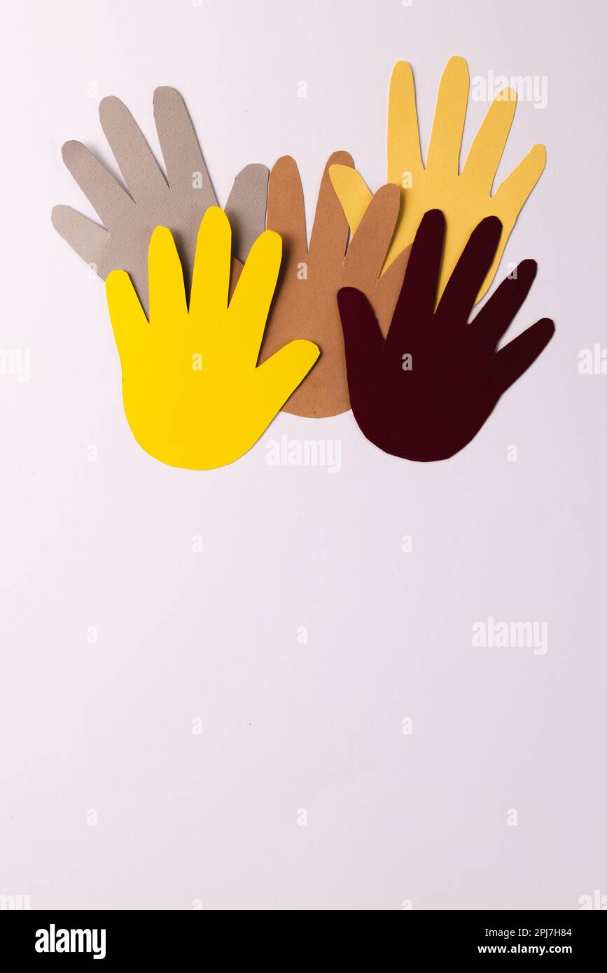 Paper cut out of multi coloured hands with copy space on white ...