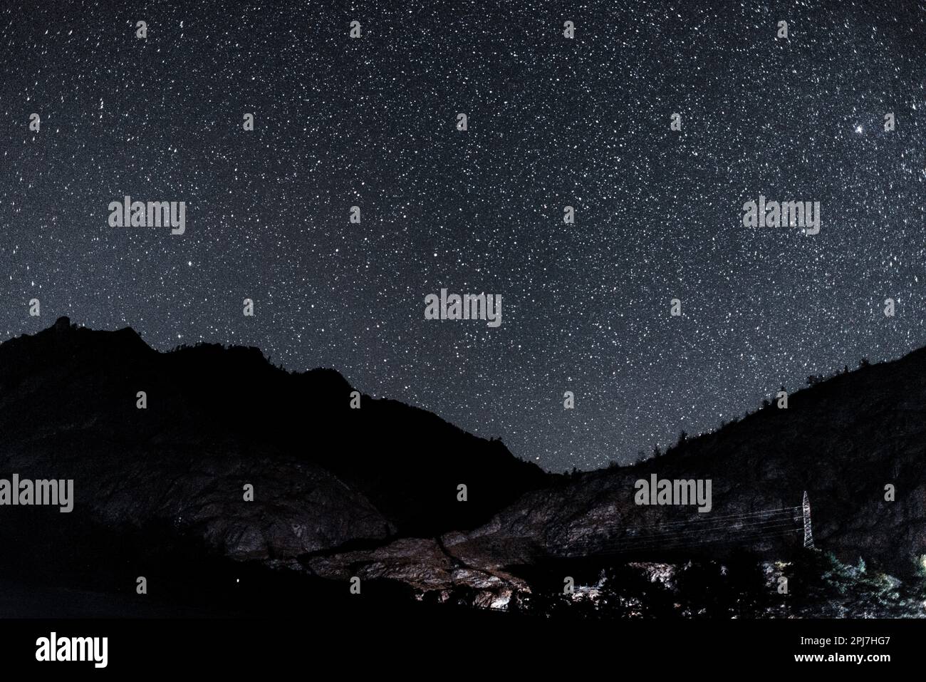 Light falls on power line poles at night under a mountain with a starry sky in Altai Stock Photo ...
