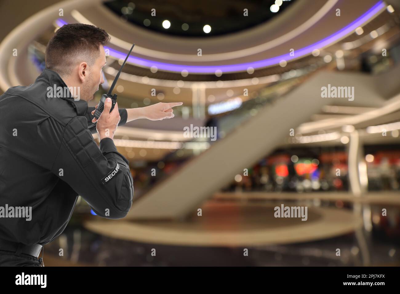 Male security guard using portable radio transmitter in shopping mall ...