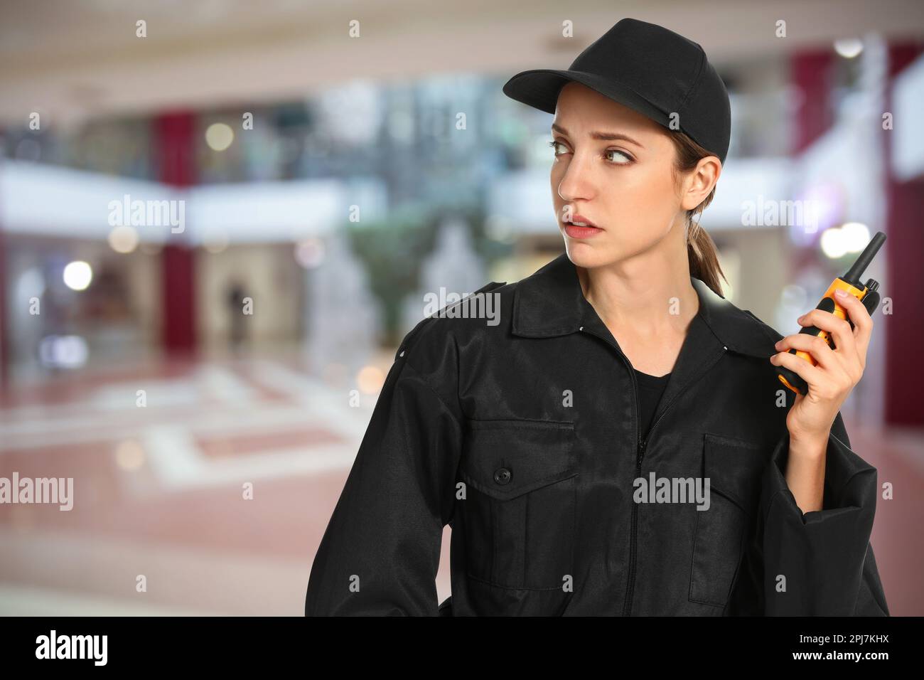 Female security guard wearing uniform using portable radio transmitter ...