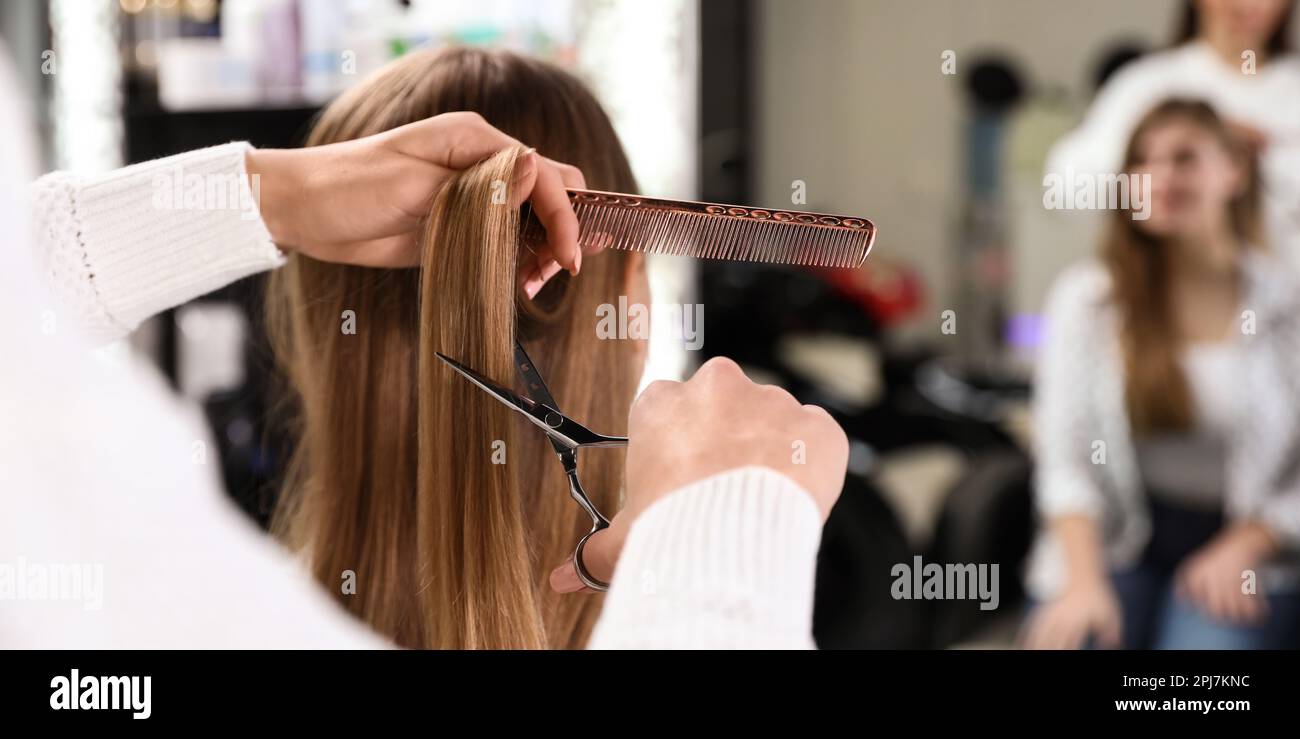 Hairdresser making stylish haircut with professional scissors in salon ...