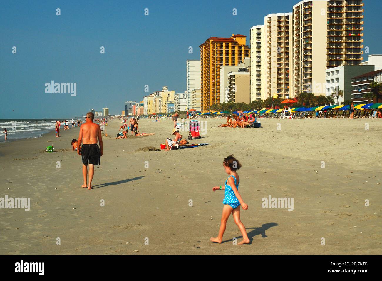 A young girl and other beachgoers walk along the Grand Strand of Myrtle ...