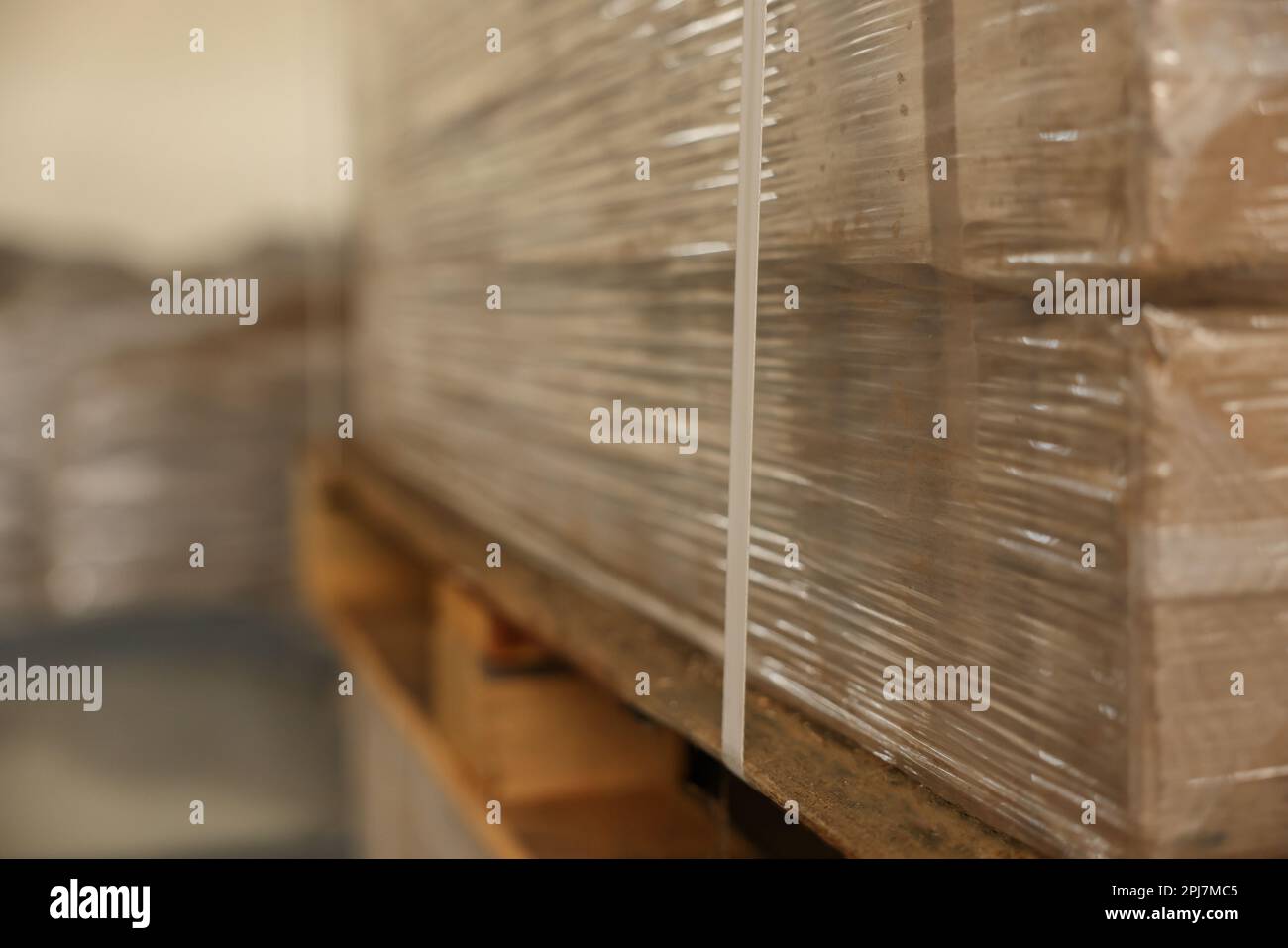 Stacks of merchandise wrapped in stretch film on wooden pallet, closeup ...