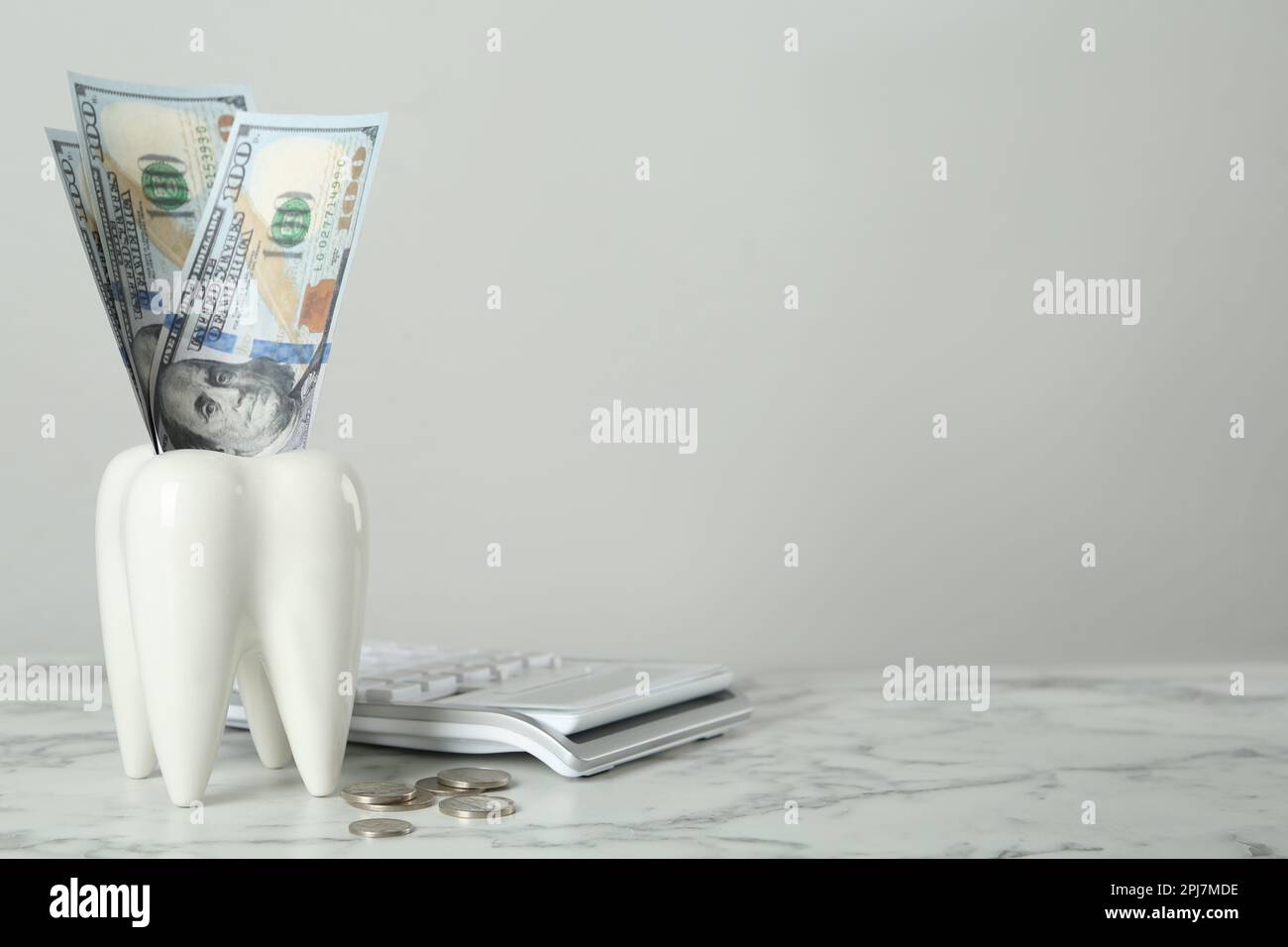 Ceramic model of tooth, money and calculator on white marble table ...