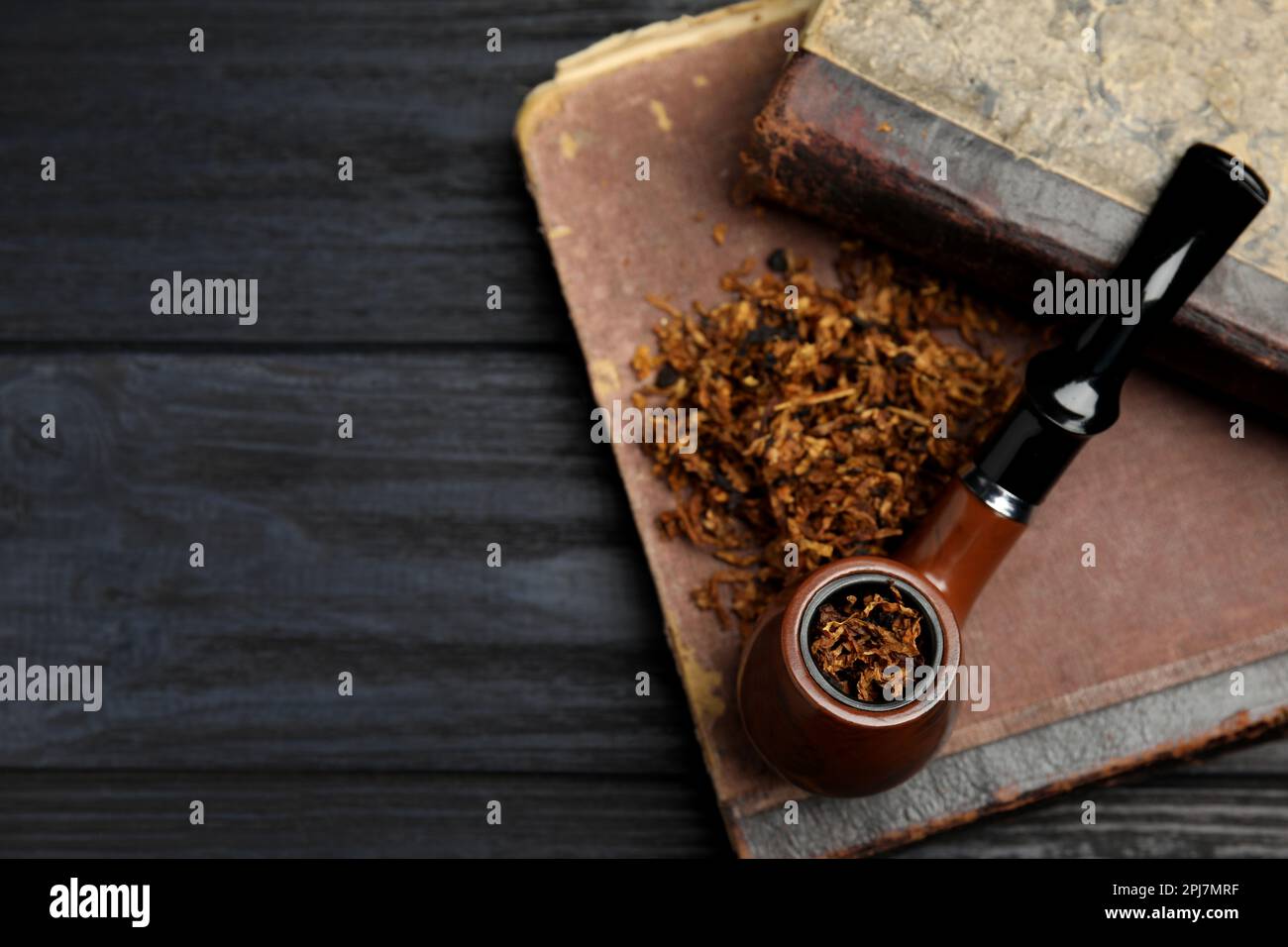 Smoking pipe, dry tobacco and old books on wooden table, top view ...