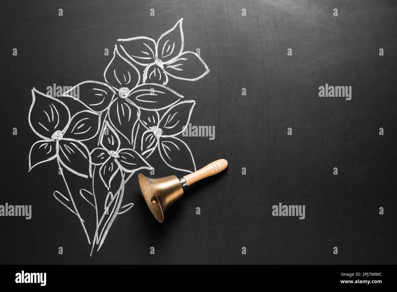 Golden bell and drawn flowers on black chalkboard, top view. School ...