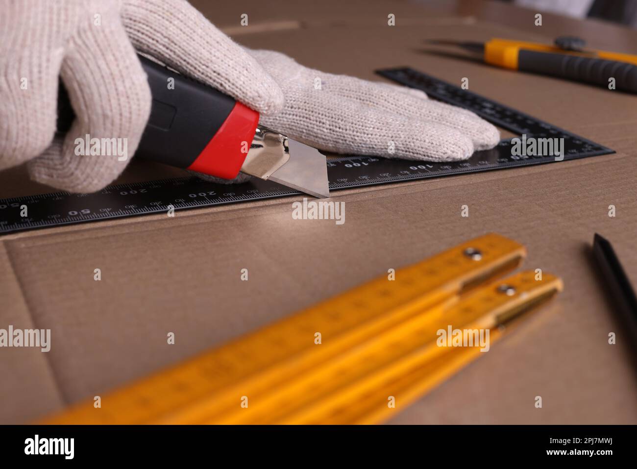 Worker cutting cardboard with utility knife and ruler, closeup Stock ...