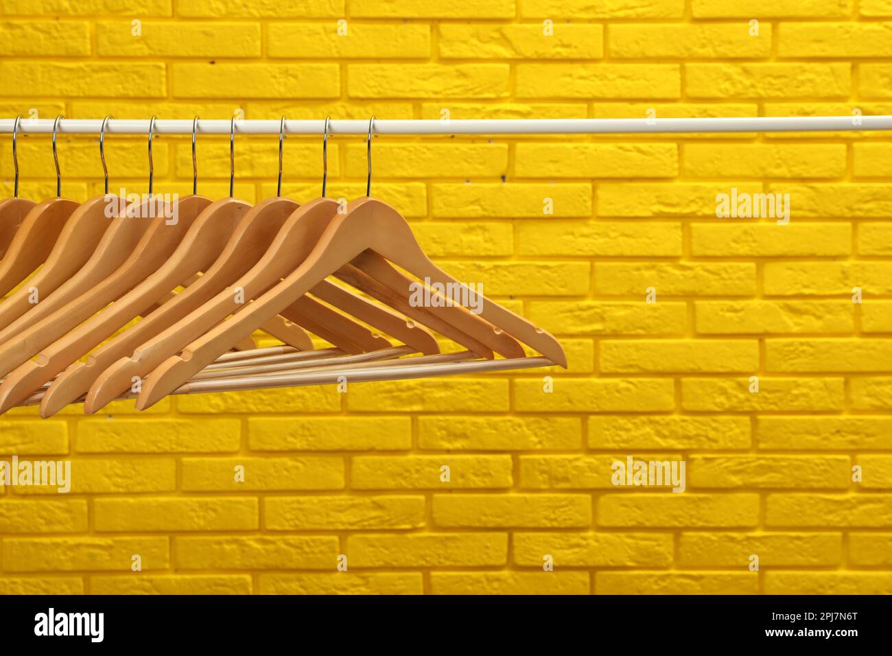 Wardrobe rack with many hangers near yellow brick wall Stock Photo - Alamy