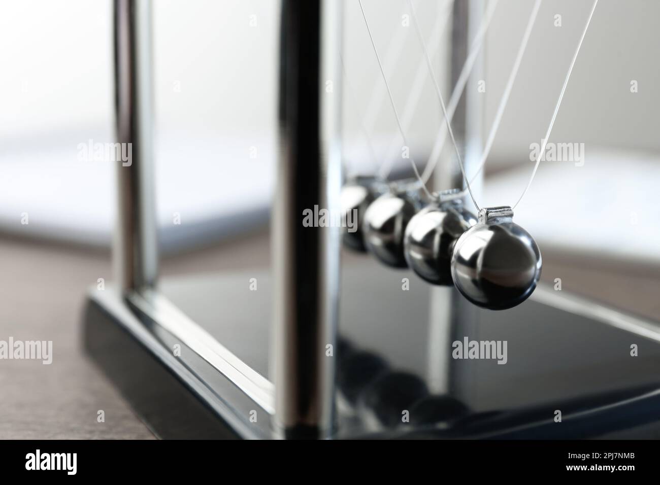 Newton's cradle on wooden table, closeup. Physics law of energy ...