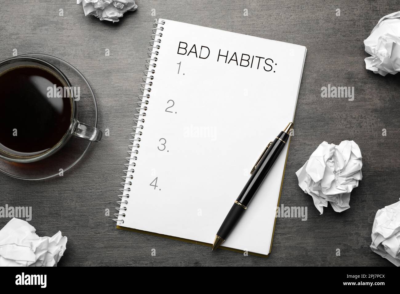 Notebook with list of bad habits, pen, crumpled paper balls and cup of ...