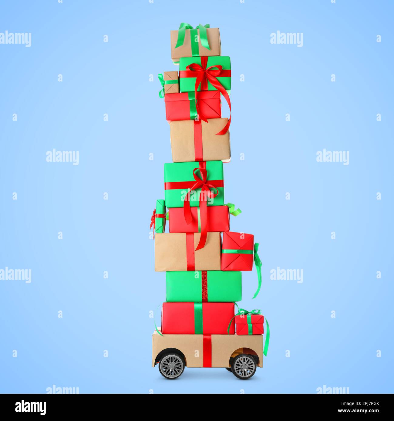 Many gifts on cardboard box with wheels against light blue background ...