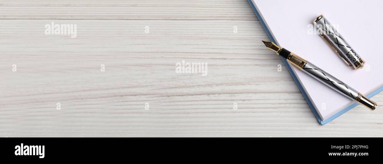 Beautiful fountain pen and notebook on white wooden table, top view ...