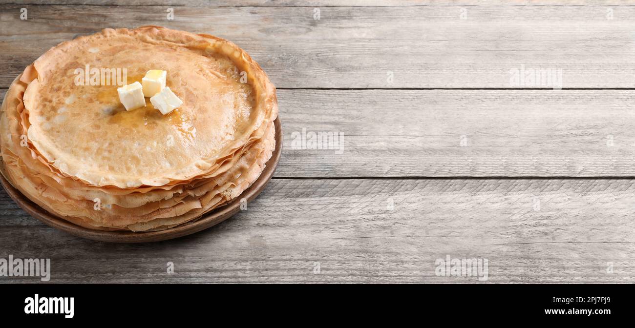 Stack of delicious crepes with melting butter on wooden table, space ...