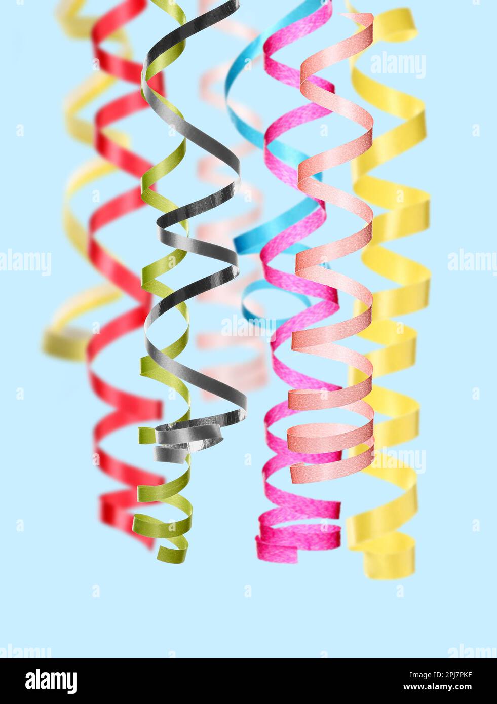 Many serpentine streamers on pale light blue background. Party decor ...